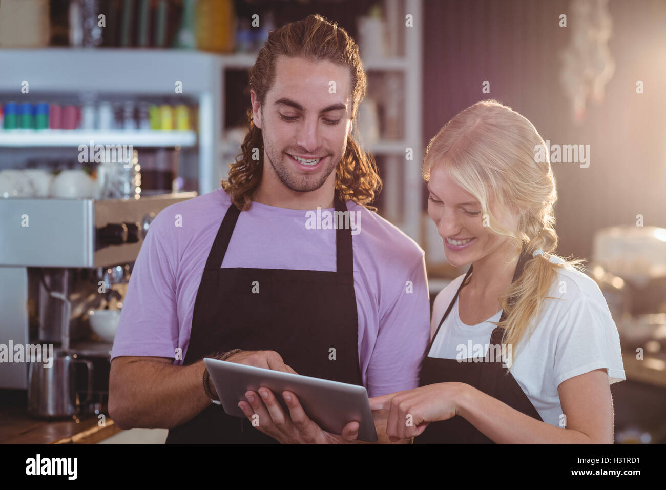 Smiling waiter and waitress using digital tablet at counter Stock Photo ...
