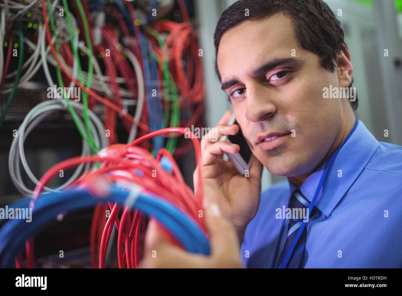 Technician talking on mobile phone while checking cables Stock Photo ...