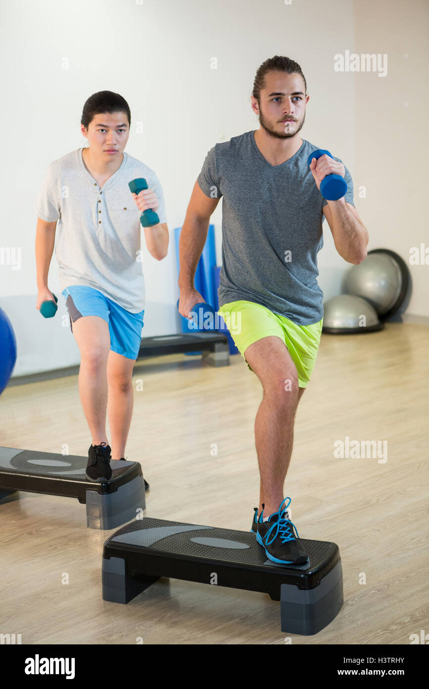 Two men doing step aerobic exercise with dumbbell on stepper Stock ...
