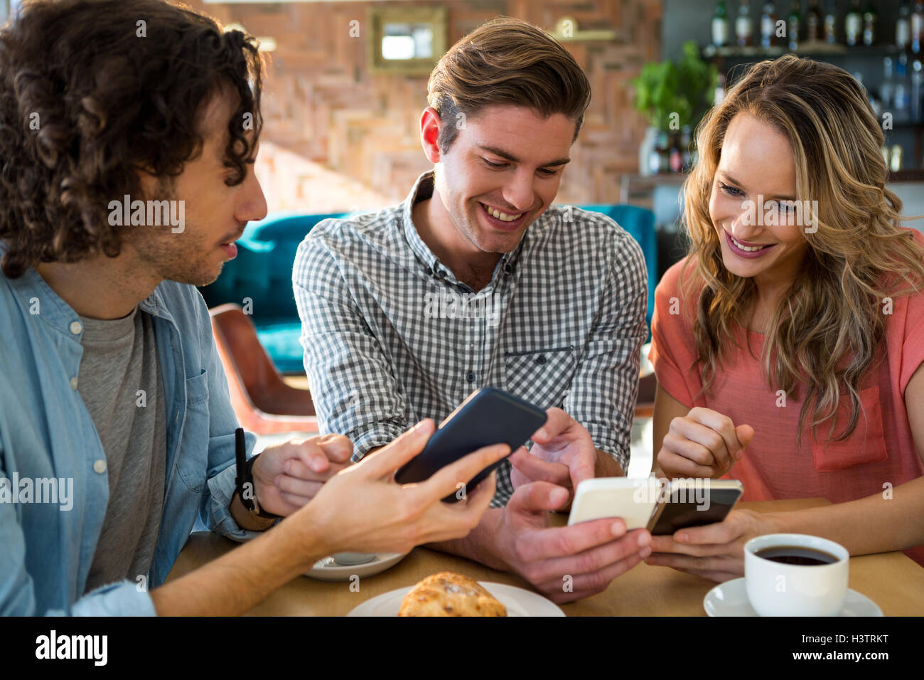 Smiling friends using their mobile phone Stock Photo - Alamy