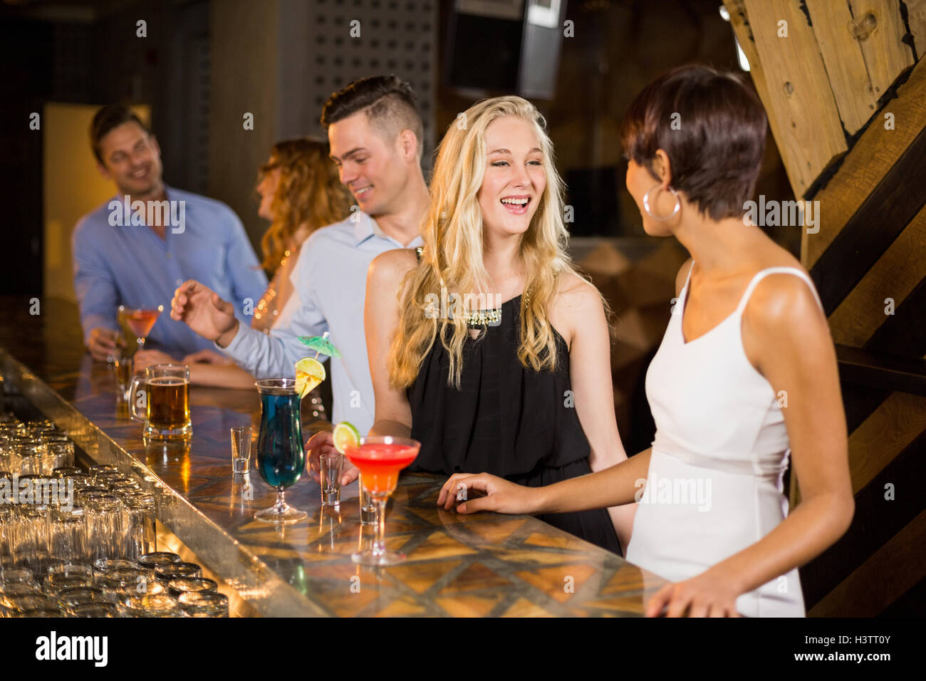 Group of friends interacting with each other at bar counter while ...