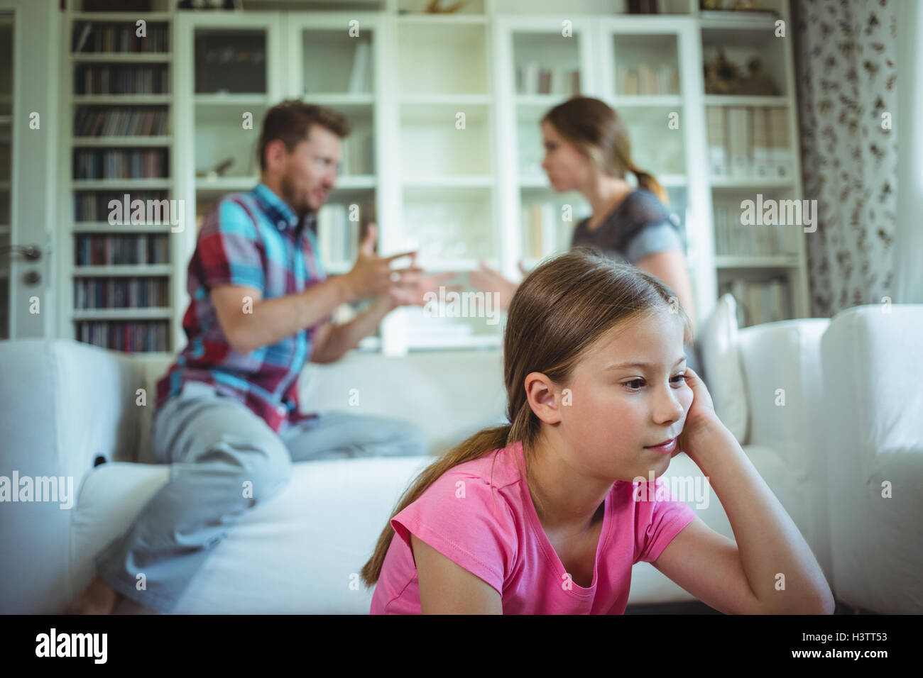 Sad girl listening to her parents arguing Stock Photo - Alamy