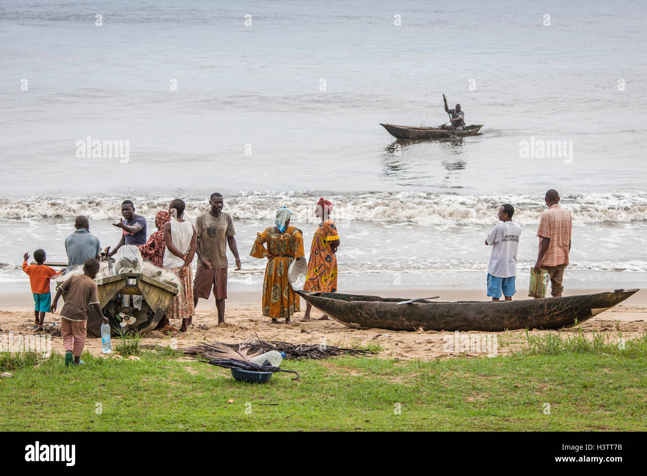 People standing near a dugout canoe on the beach, Kribi, South Region ...