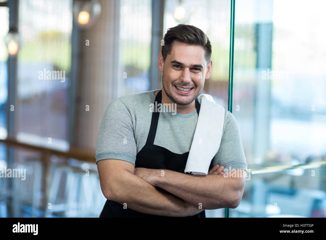 Smiling waiter leaning on glass door in caf├⌐ Stock Photo - Alamy