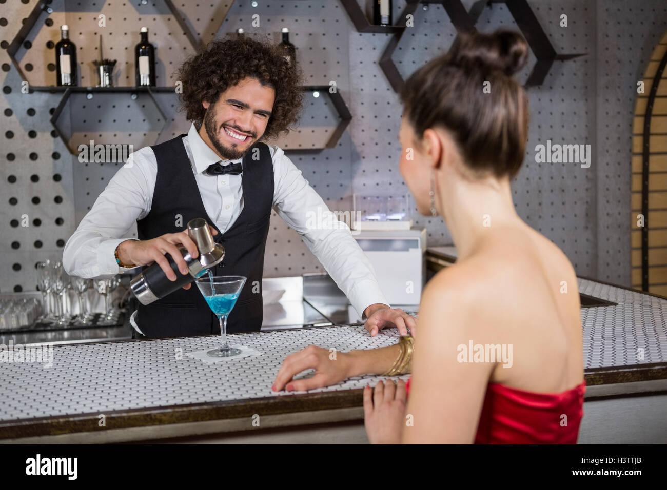 Waiter pouring cocktail in womans glass at bar counter Stock Photo - Alamy