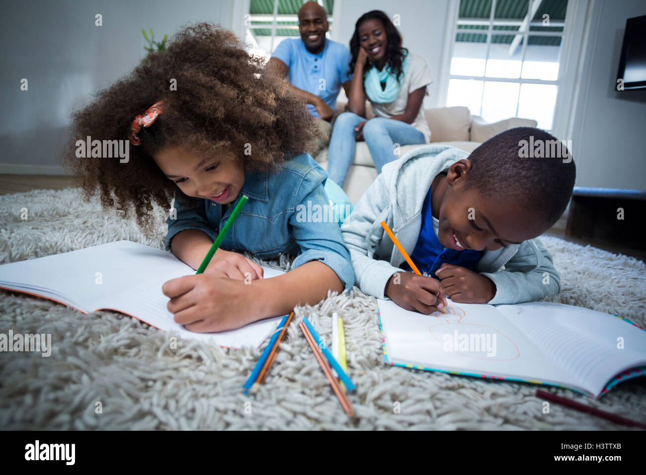 Children doing their homework with parents in background Stock Photo - Alamy