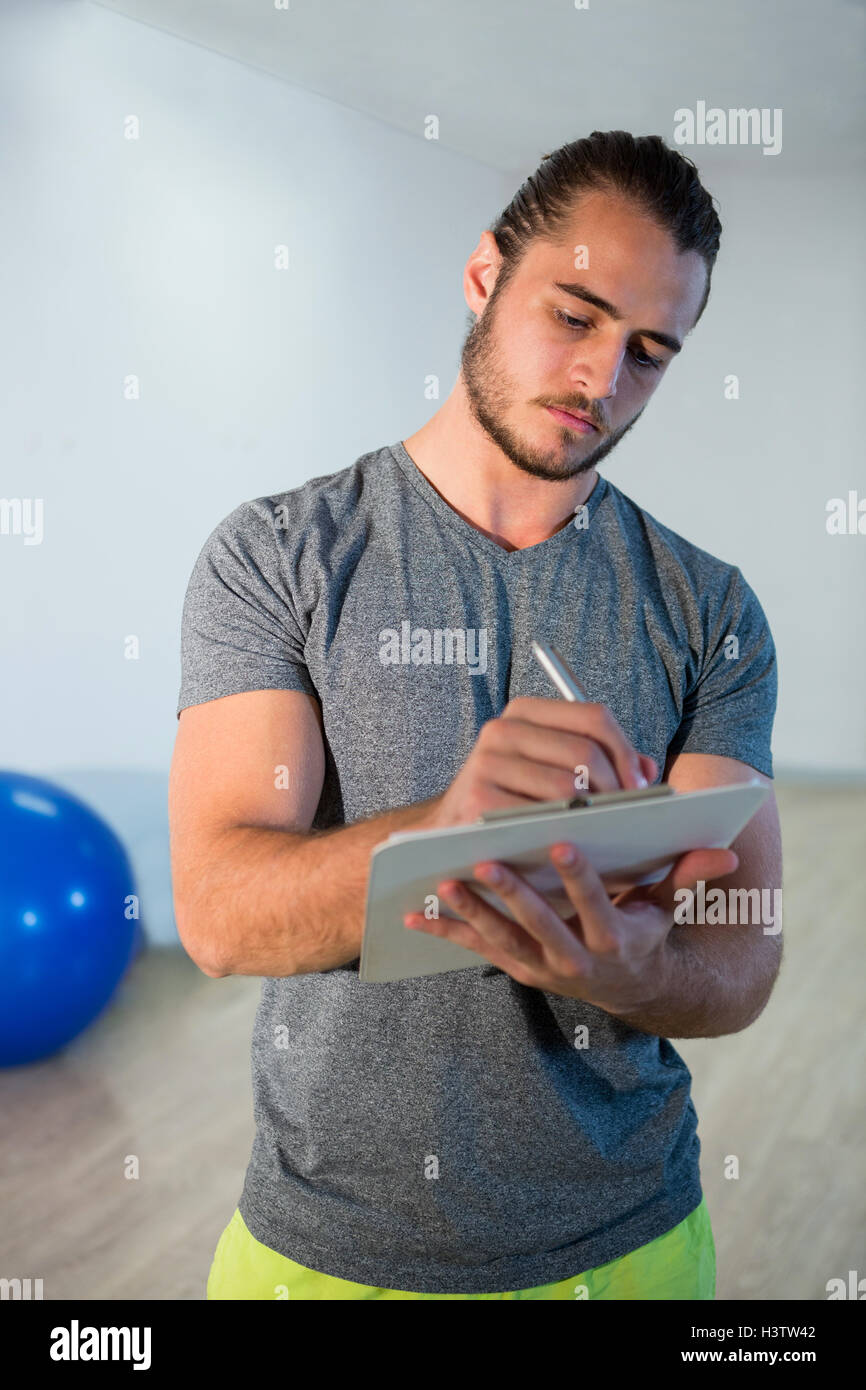 Fitness trainer writing on clipboard Stock Photo - Alamy