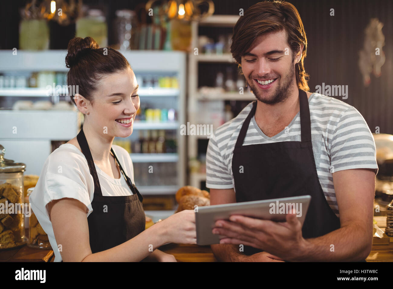 Smiling waiter and waitress using digital tablet at counter Stock Photo ...