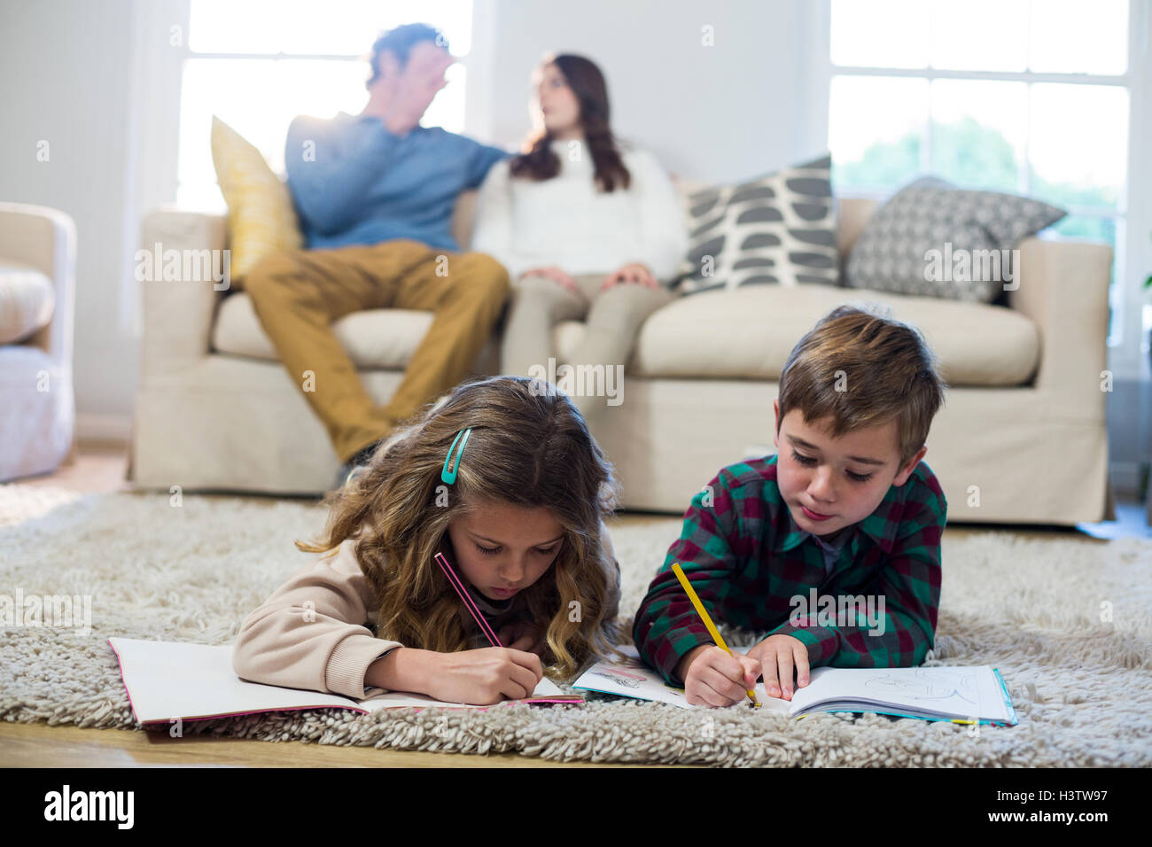 Children doing homework with parents in background Stock Photo - Alamy