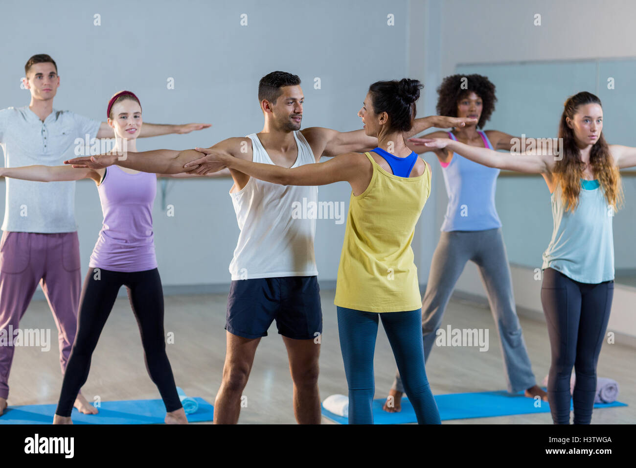 Yoga instructor helping student with a correct pose Stock Photo - Alamy