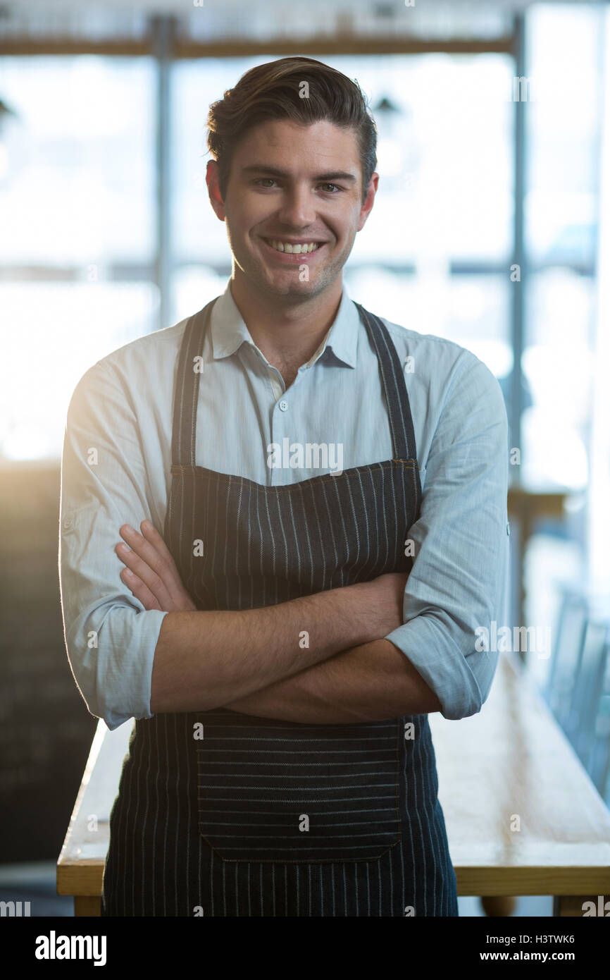 Portrait of smiling waiter standing with arms crossed Stock Photo - Alamy