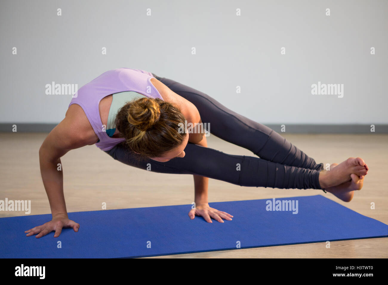 Woman doing eight angle pose on exercise mat Stock Photo - Alamy