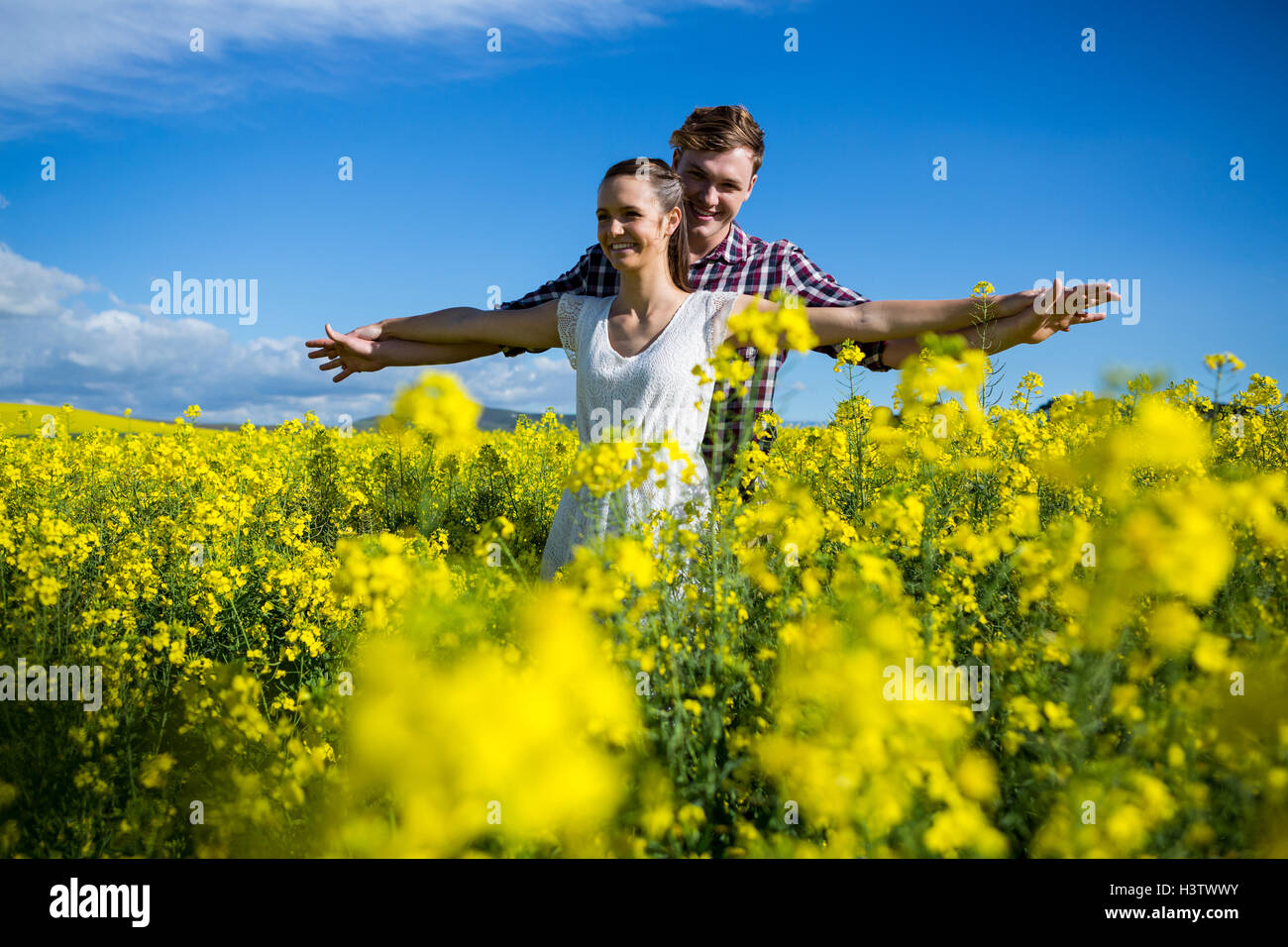 Romantic couple standing with arms outstretched in mustard field Stock ...