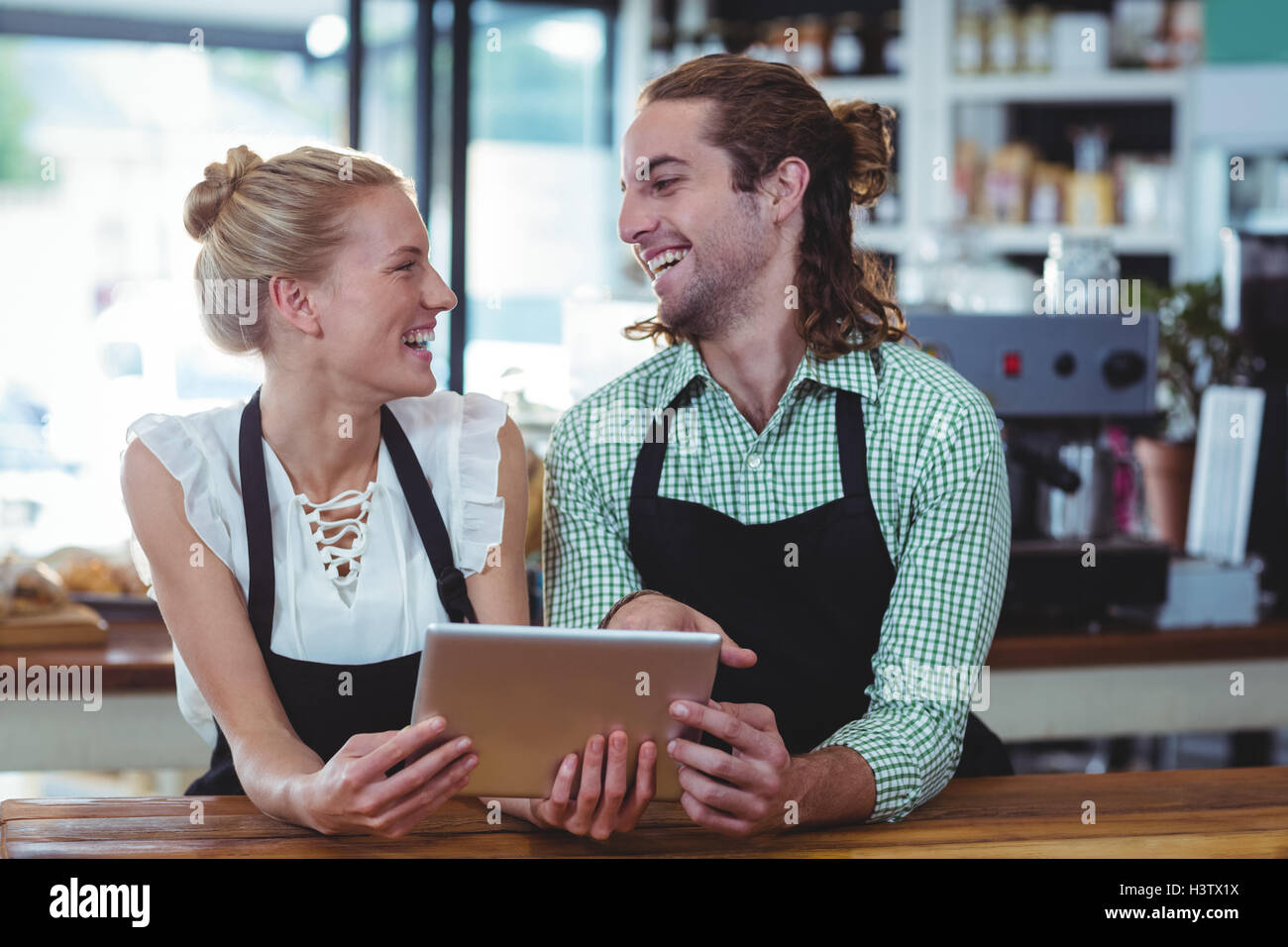 Smiling waiter and waitress standing at counter using digital Stock ...