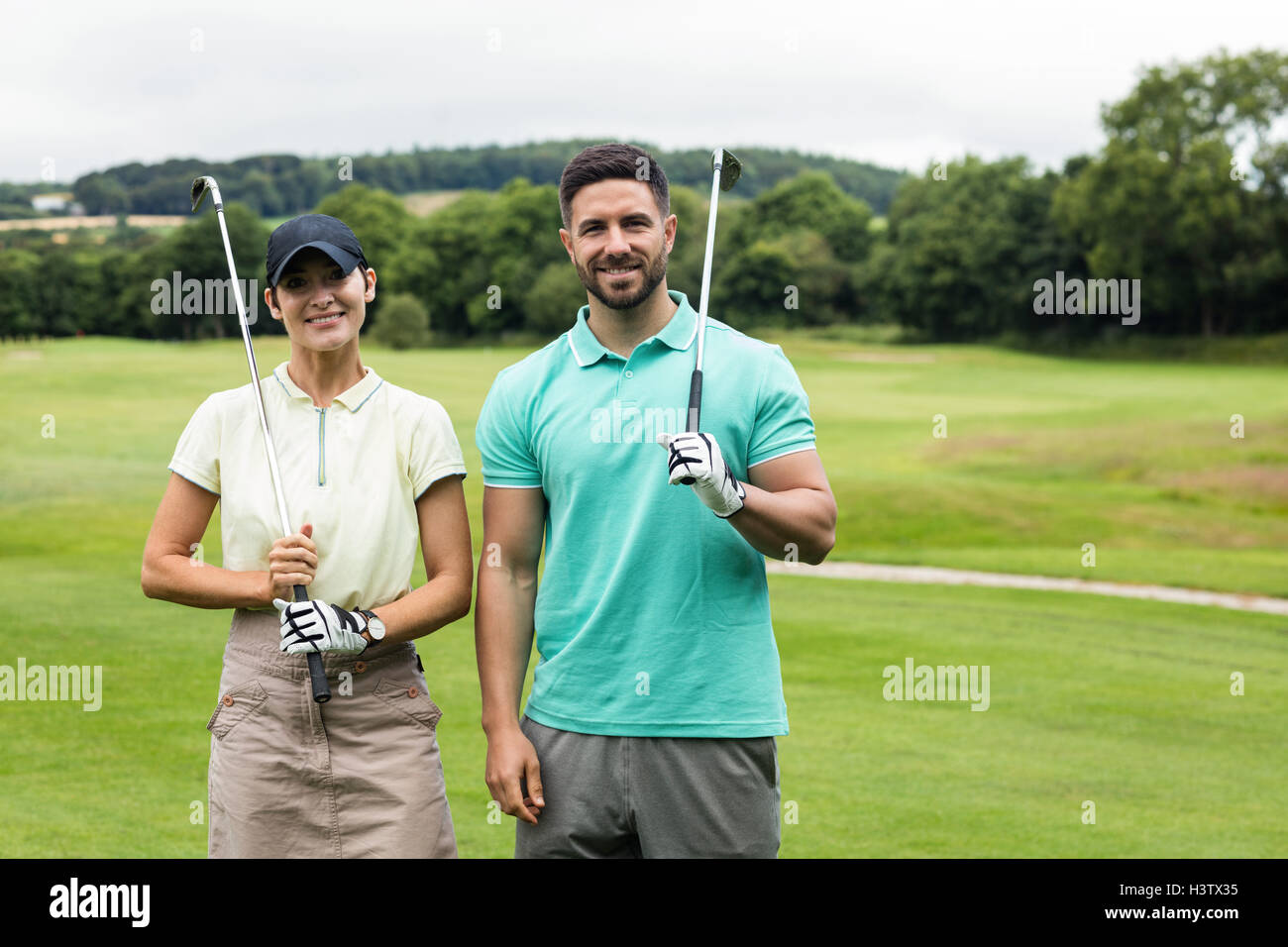Couple standing with golf club in golf course Stock Photo - Alamy