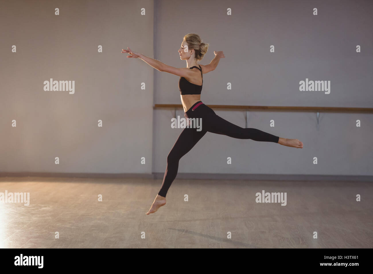 Woman leaping while performing stretching exercise Stock Photo - Alamy