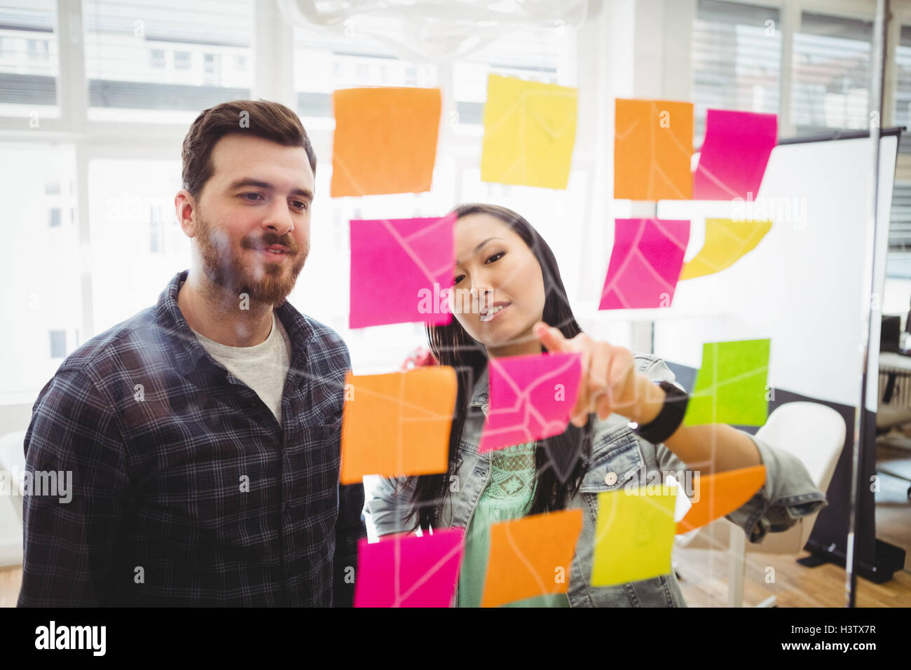 Business people looking at multi colored sticky notes on glass Stock ...