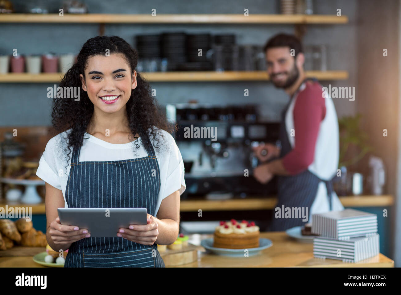 Smiling waitress using digital tablet at counter in caf├⌐ Stock Photo ...