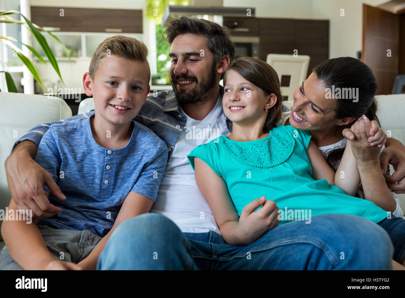 Happy family sitting with arm around on sofa Stock Photo - Alamy