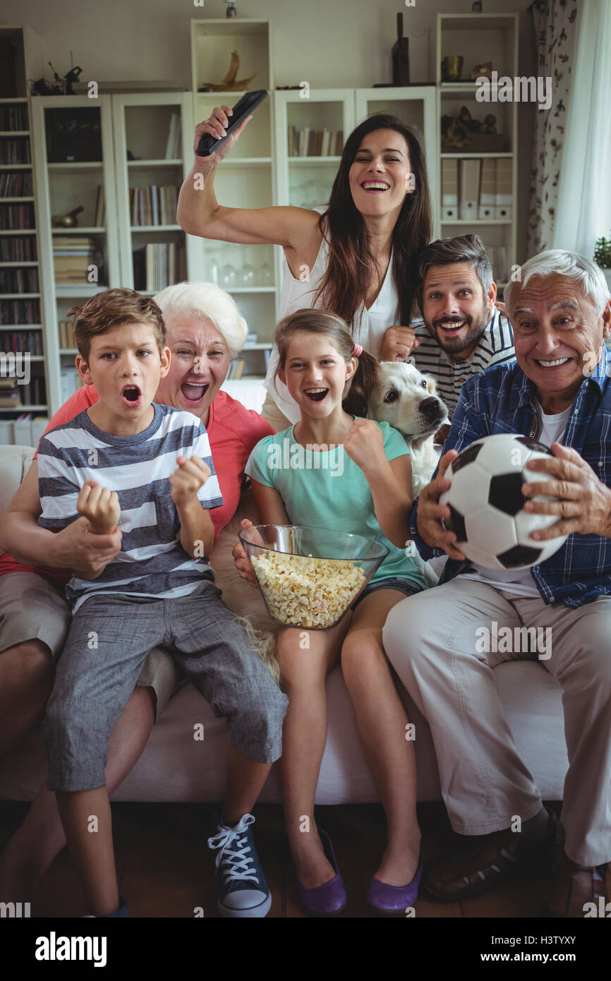 Happy multi-generation family watching soccer match on television in ...