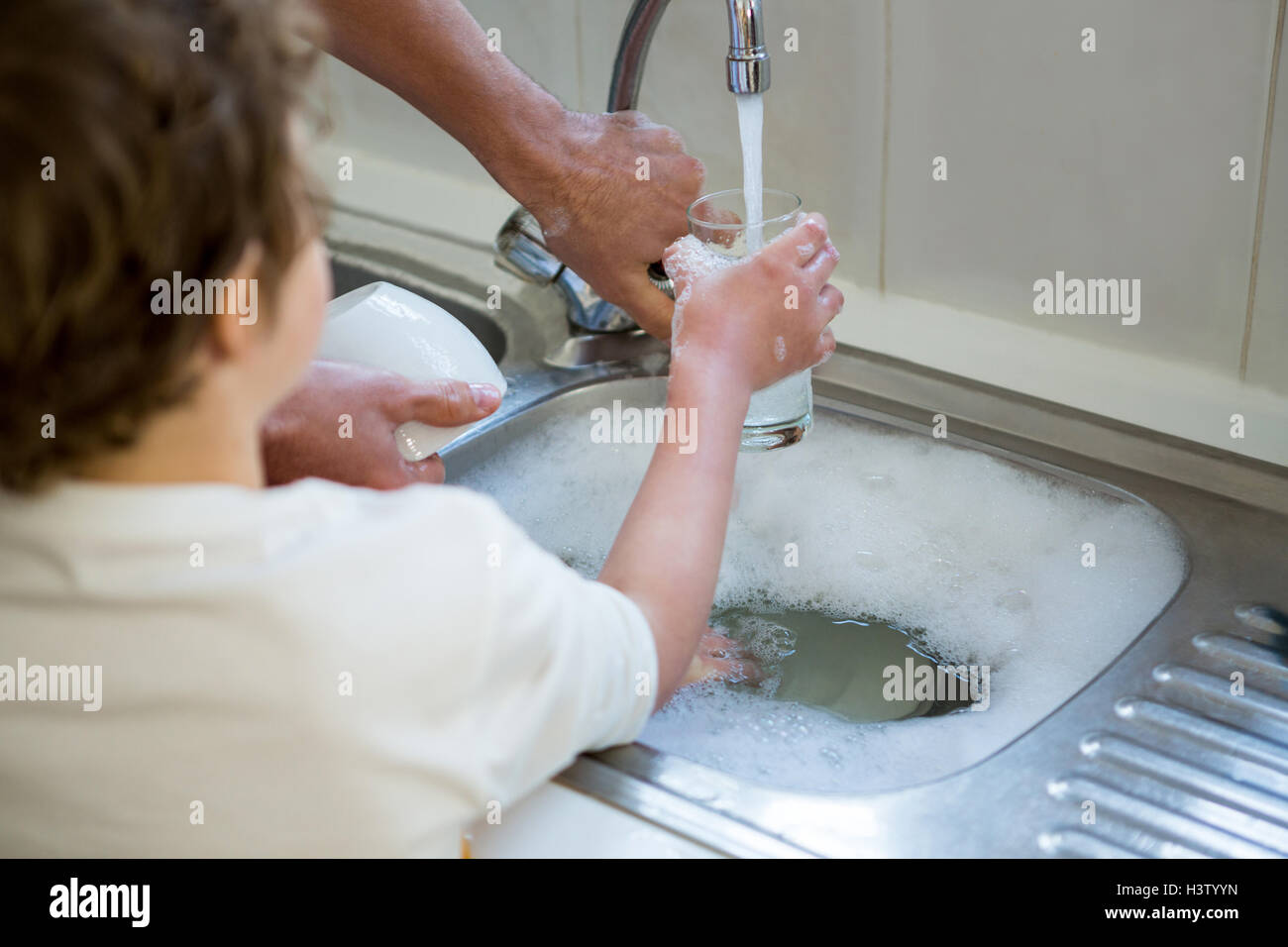 Son helping father in washing utensils Stock Photo - Alamy