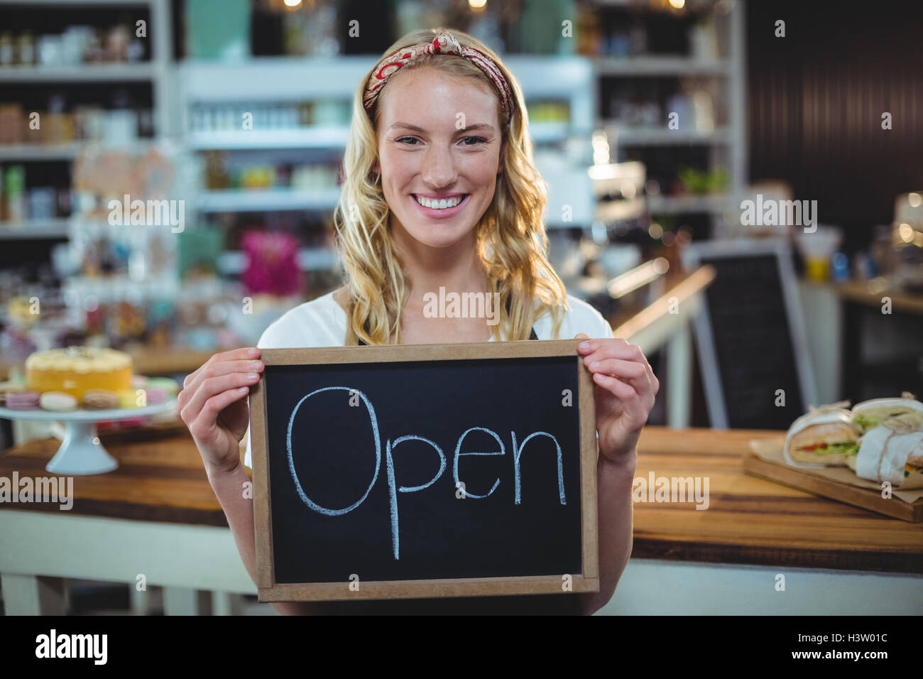 Smiling waitress showing chalkboard with open sign Stock Photo - Alamy