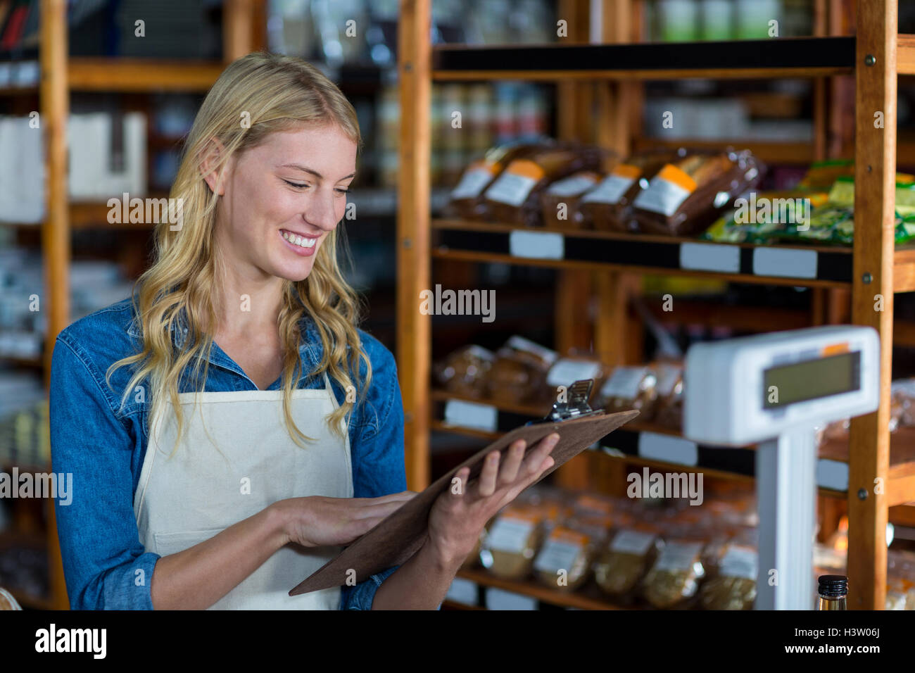 Smiling female staff looking at clipboard Stock Photo - Alamy
