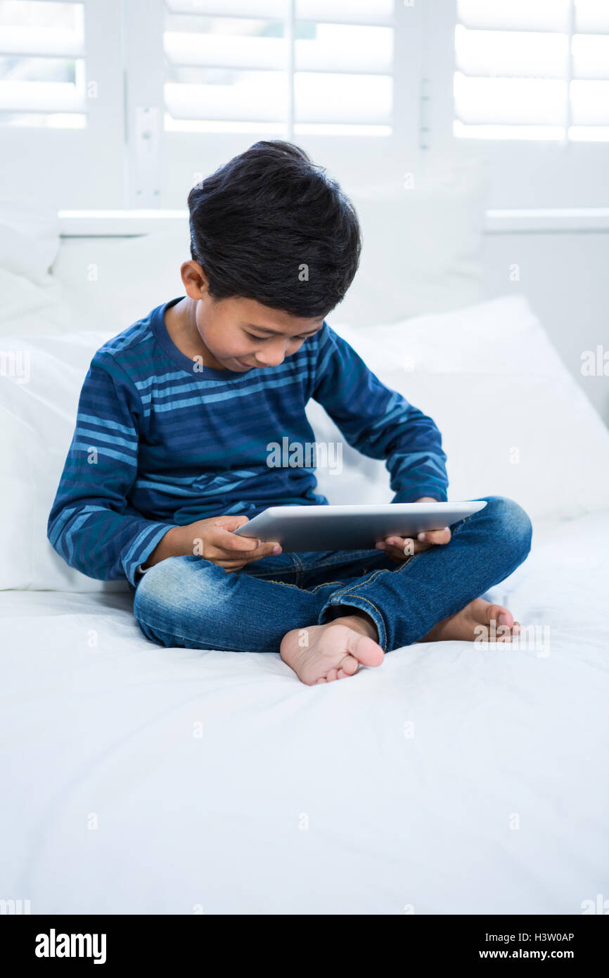 Boy using digital tablet while relaxing on bed Stock Photo - Alamy