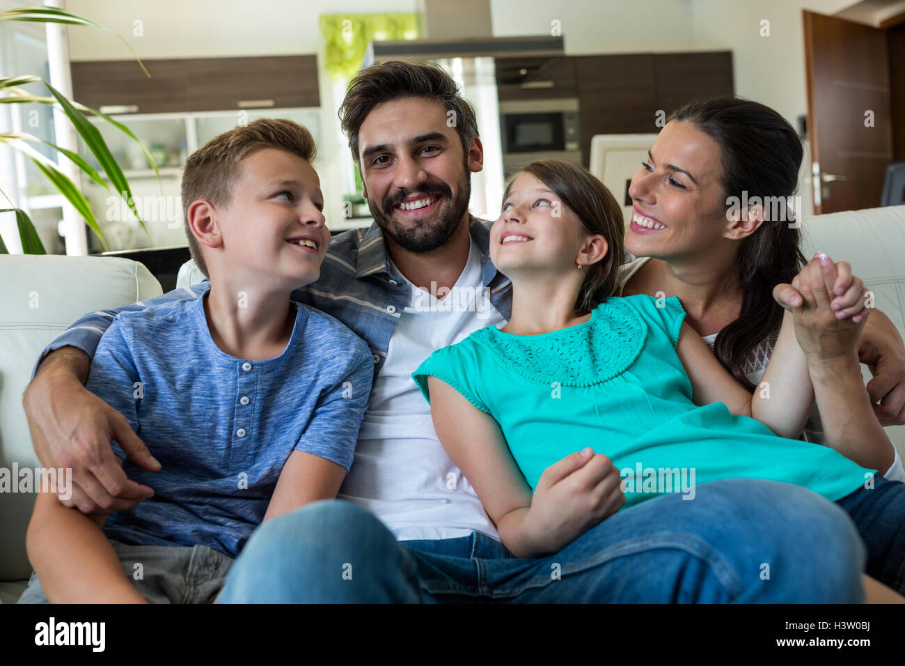 Happy family sitting with arm around on sofa Stock Photo - Alamy