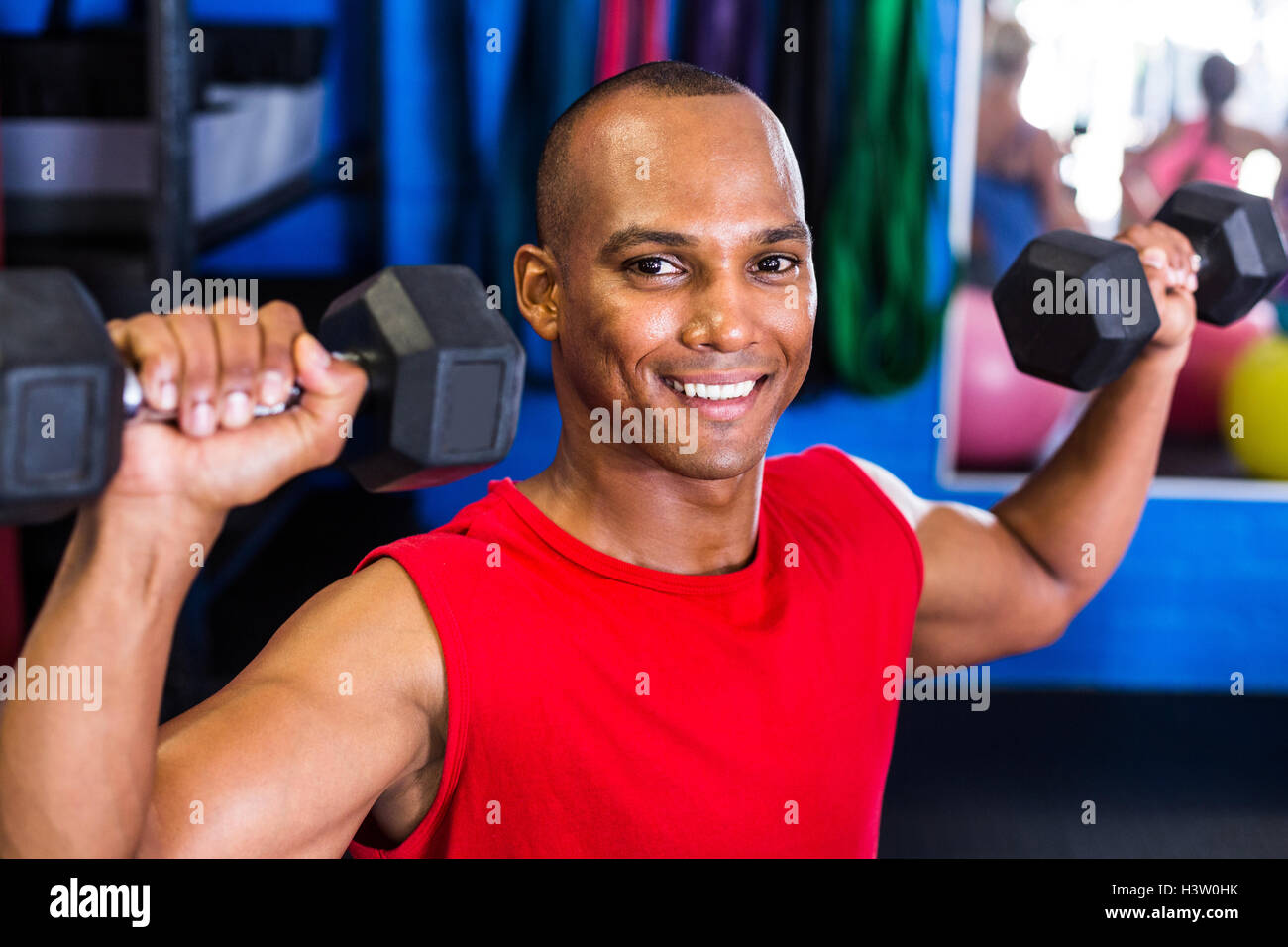 Portrait of happy man lifting dumbbell in gym Stock Photo - Alamy