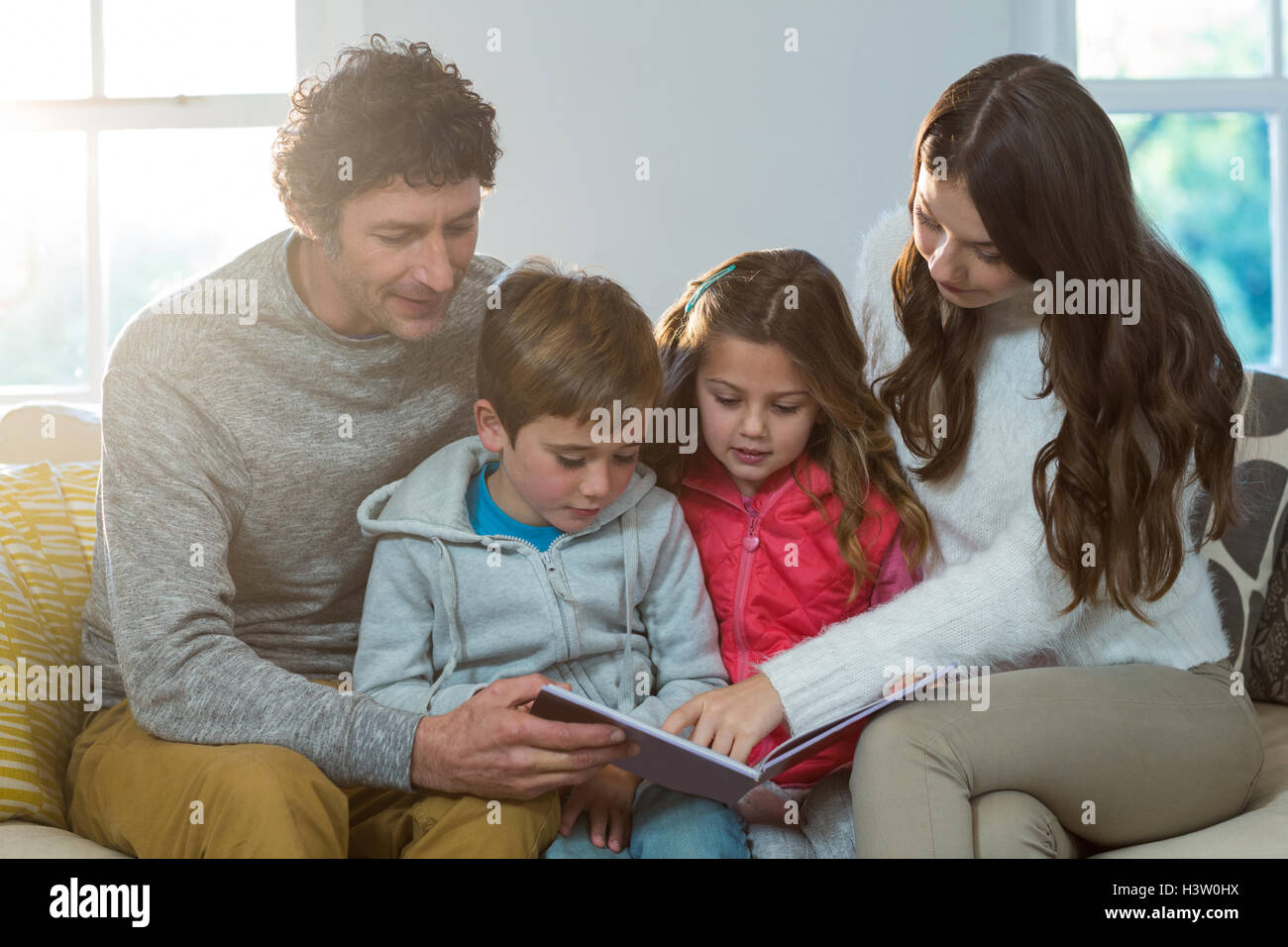 Family reading a book Stock Photo - Alamy