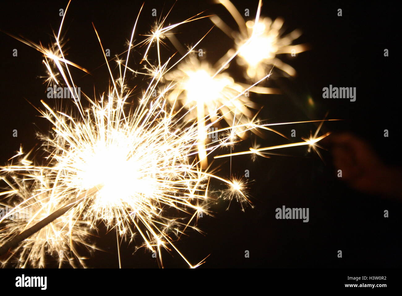 Three sparklers on New Year's Eve Stock Photo - Alamy