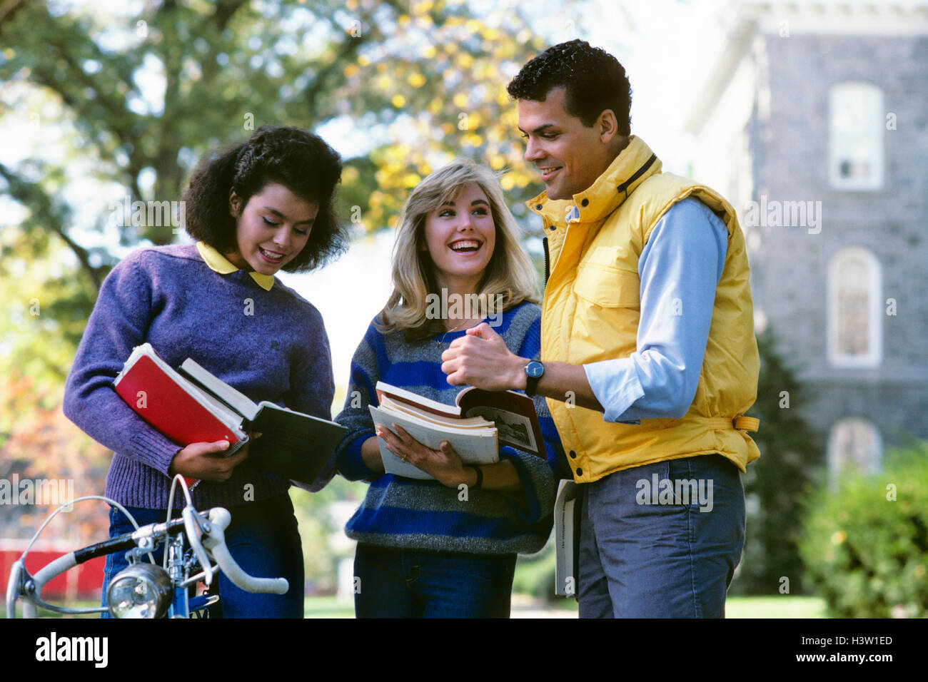 1980s THREE COLLEGE STUDENTS COMPARING NOTES ON CAMPUS Stock Photo - Alamy