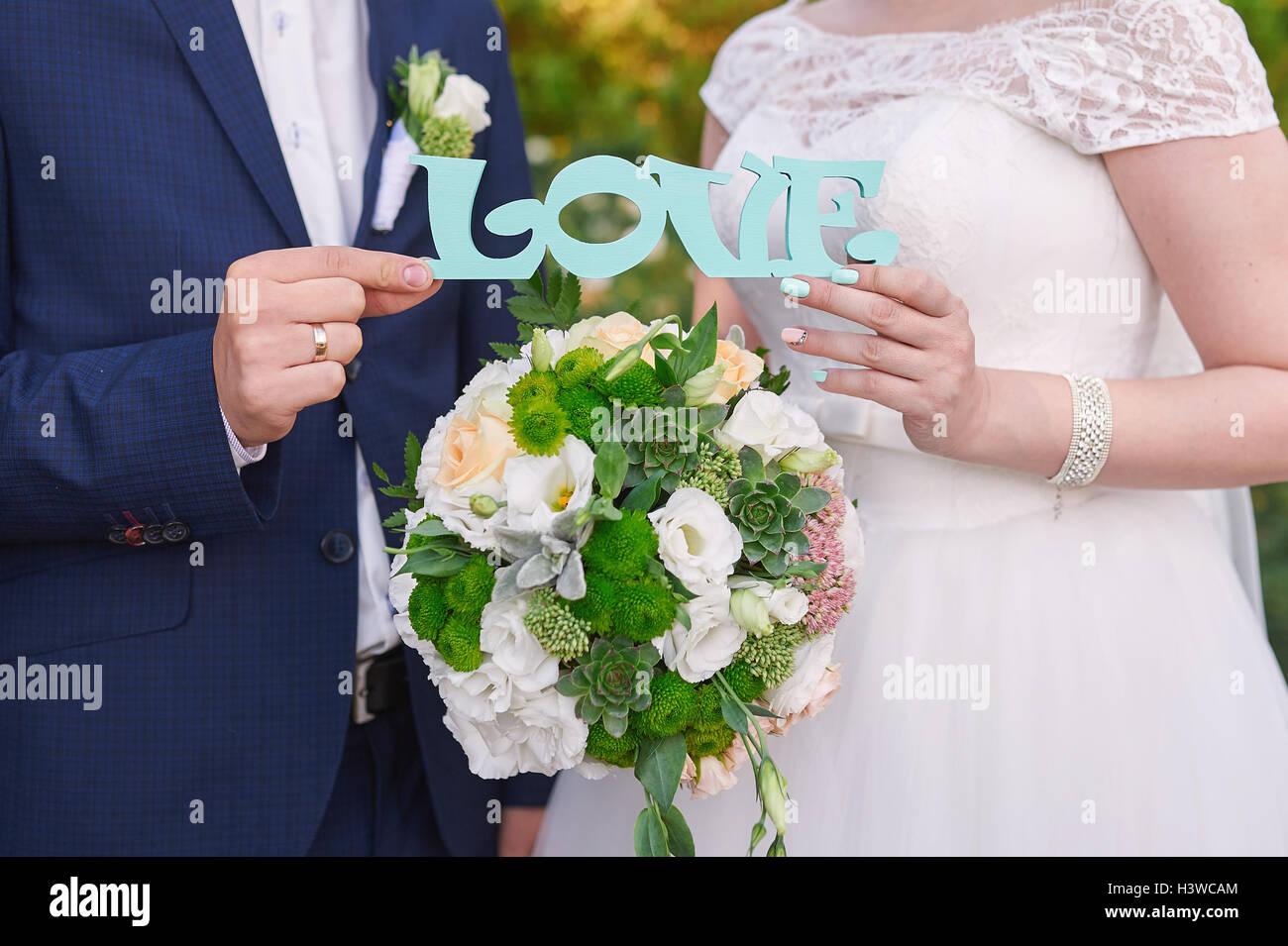 bride and groom holding wooden word love Stock Photo - Alamy