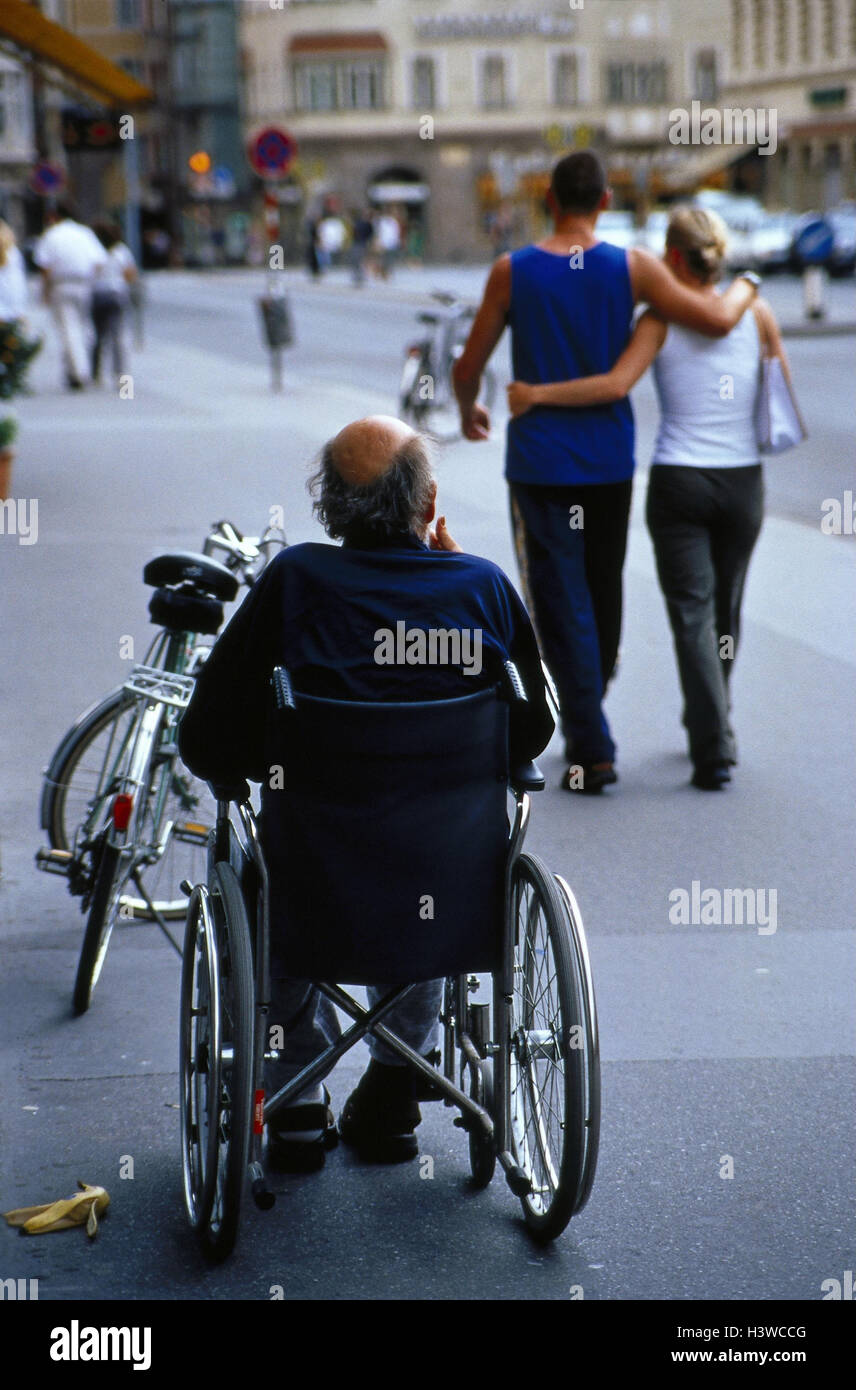 Town, street scene, invalid's wheel chair driver, couple, embrace ...
