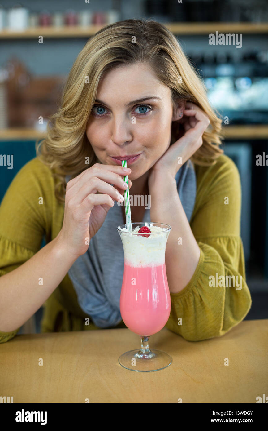 Portrait of woman drinking milkshake with a straw Stock Photo - Alamy