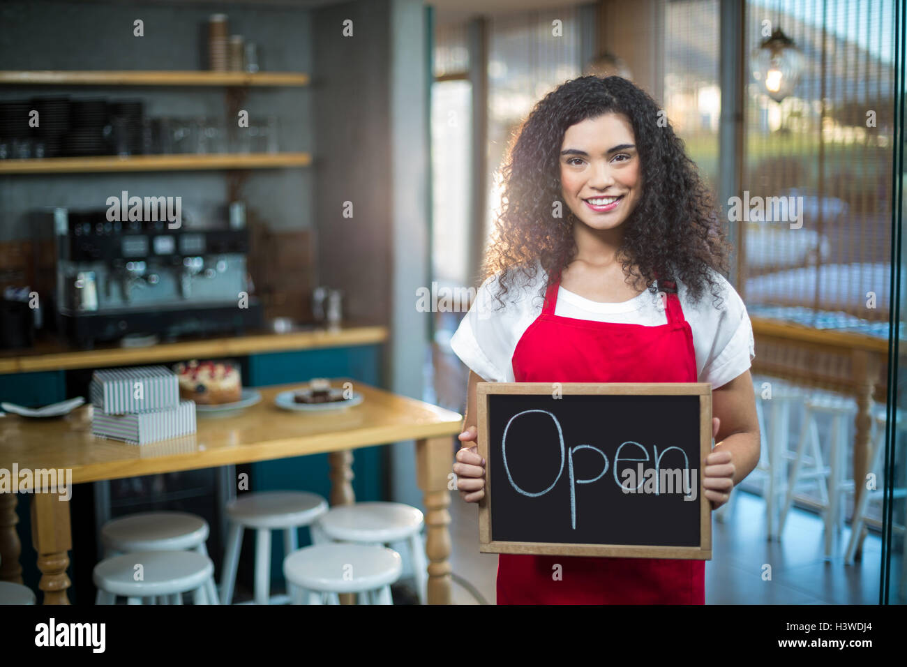 Smiling waitress showing slate with open sign Stock Photo - Alamy