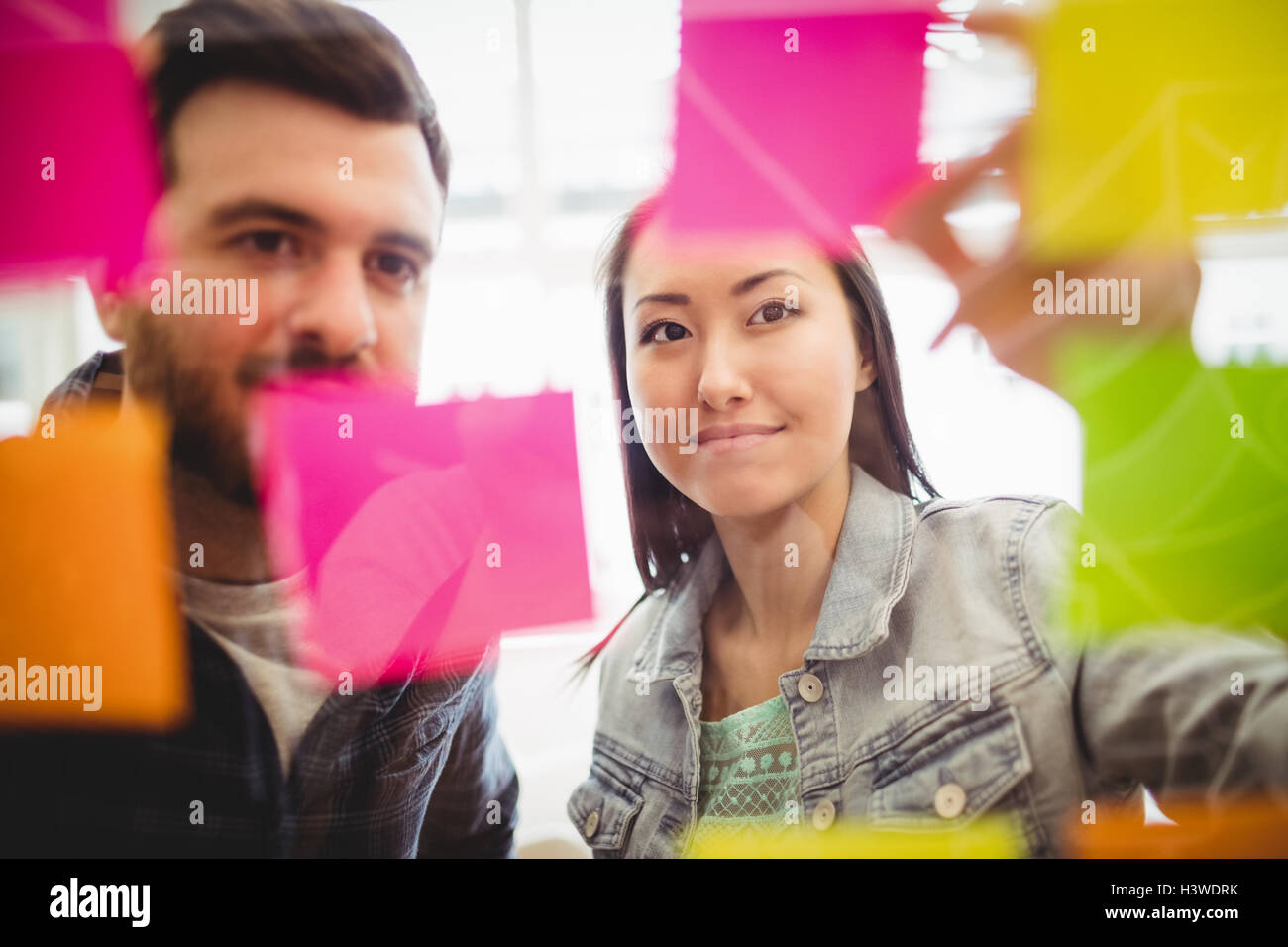 Business people looking at multi colored sticky notes on glass Stock ...