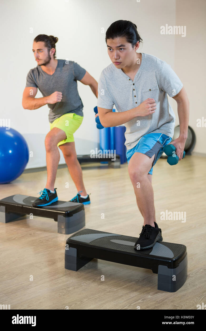 Two men doing step aerobic exercise with dumbbell on stepper Stock ...