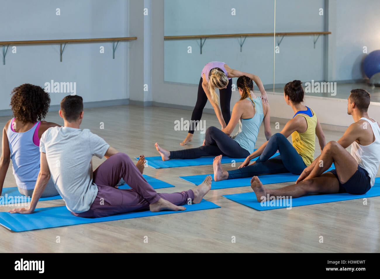 Yoga instructor helping student with a correct pose Stock Photo - Alamy