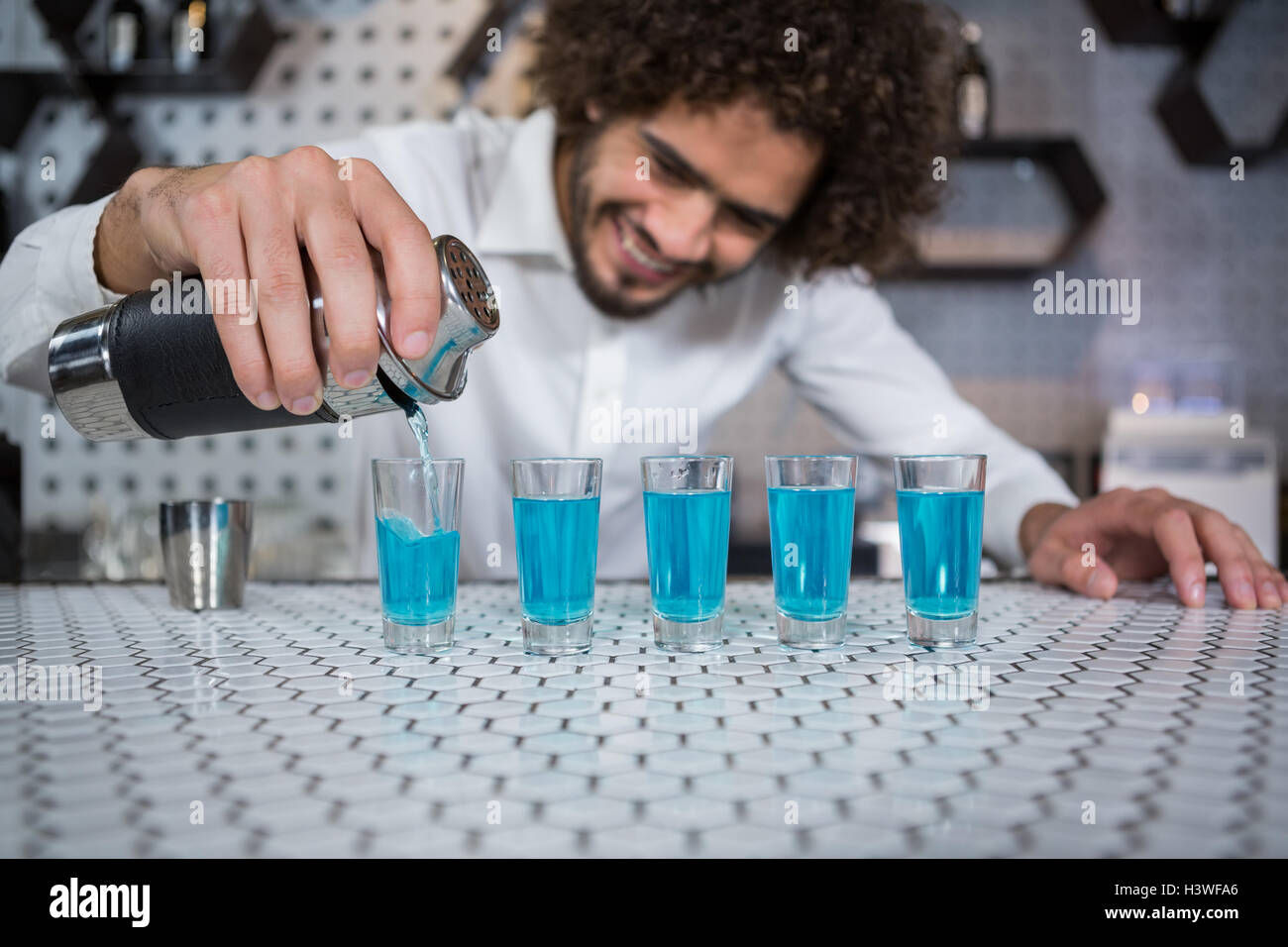 Bartender pouring cocktail into shot glasses Stock Photo - Alamy