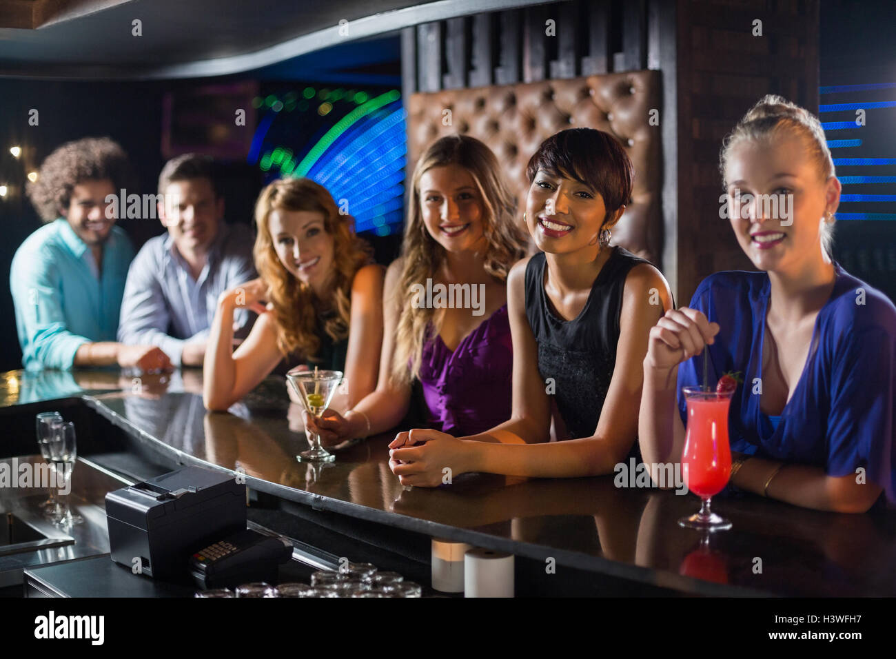 Smiling friends standing together at bar counter Stock Photo - Alamy