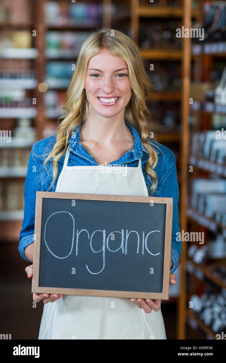 Portrait of smiling female staff holding a organic sign board Stock ...