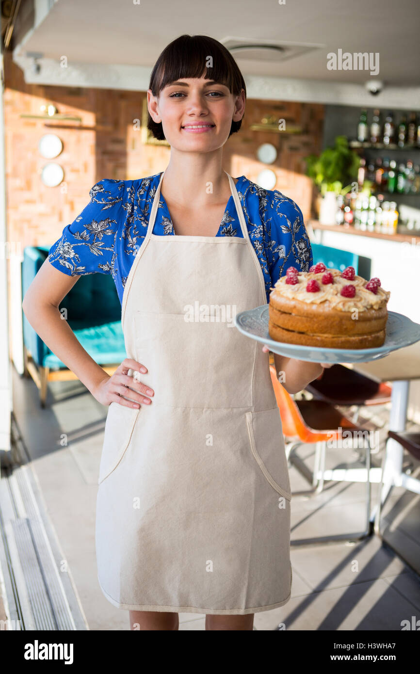 Portrait of smiling waitress holding a cake Stock Photo - Alamy