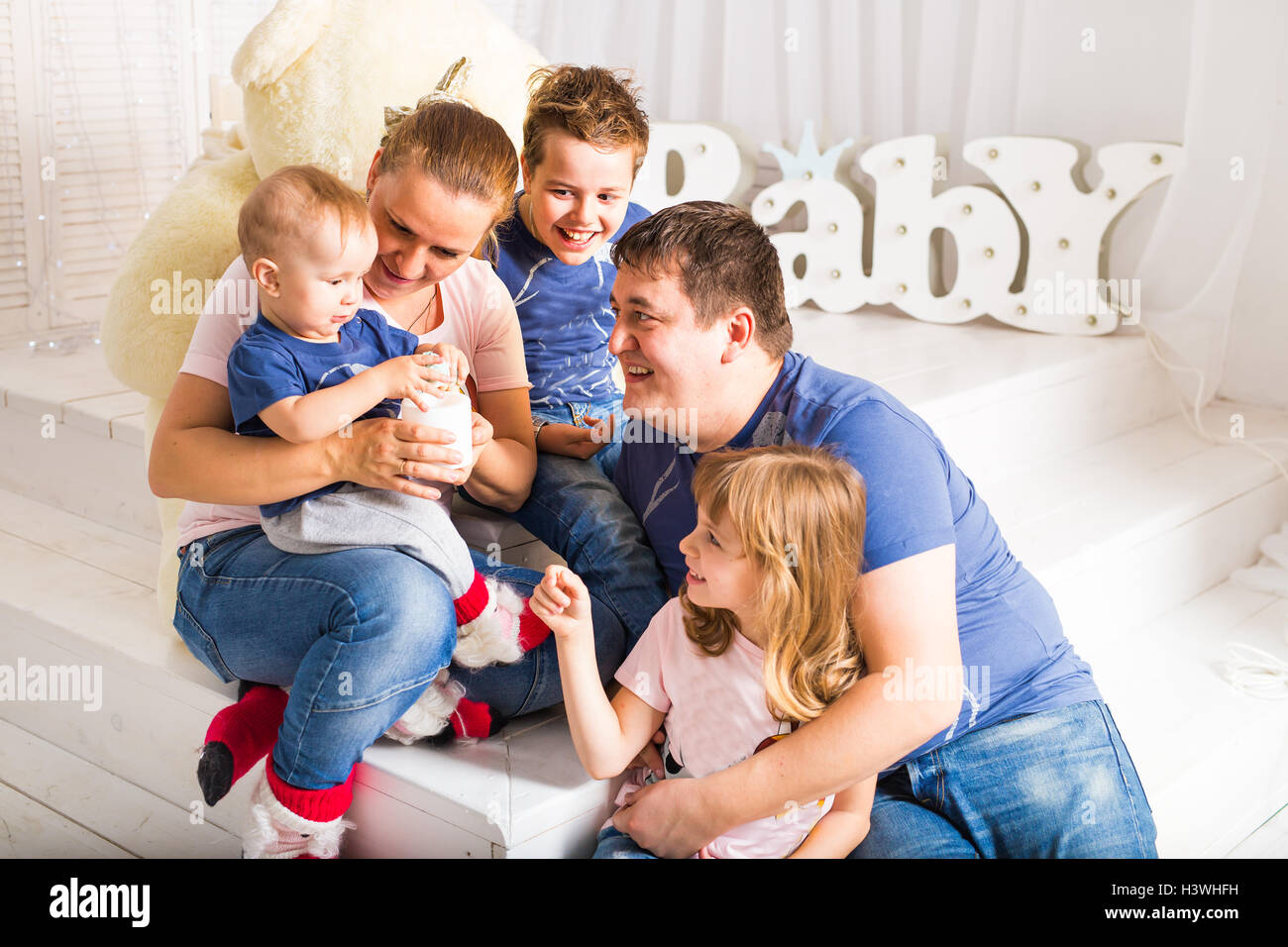 Happy family with 3 children sitting on floor of living room at home ...