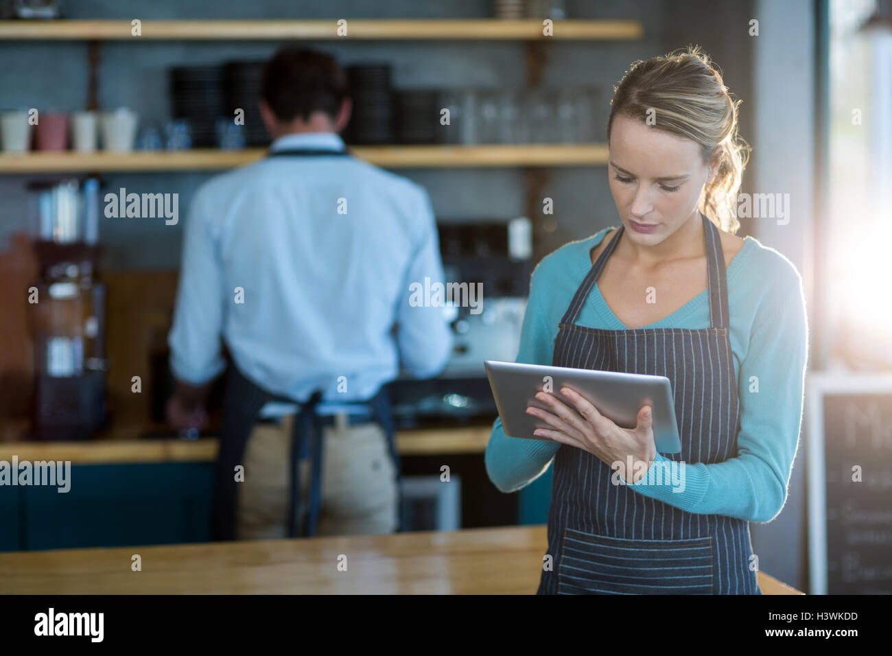 Waitress using digital tablet at counter Stock Photo - Alamy