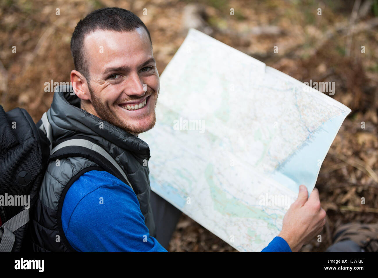 Male hiker holding a map in forest Stock Photo - Alamy
