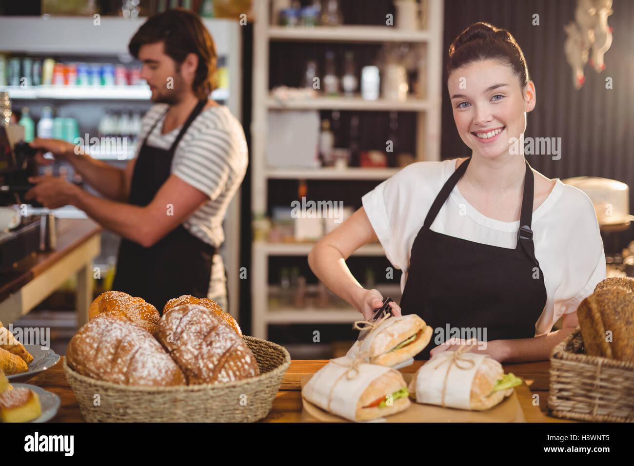 Portrait of waitress standing at counter with sandwiches and bread roll ...