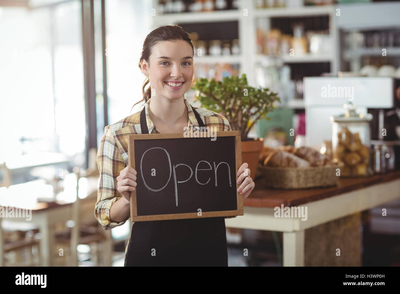 Portrait of waitress showing chalkboard with open sign Stock Photo - Alamy