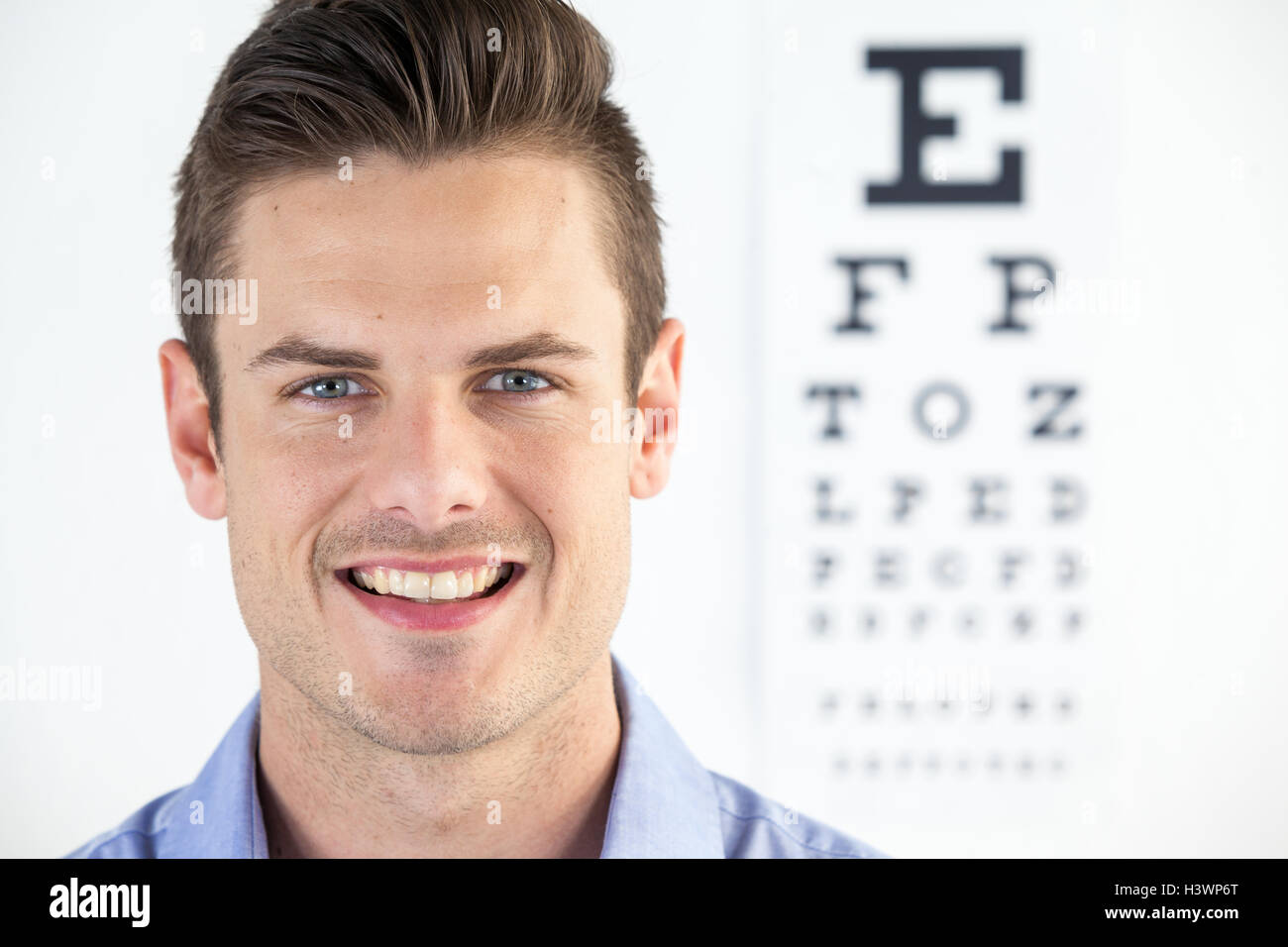 Man wearing contact lens with eye chart in background Stock Photo - Alamy